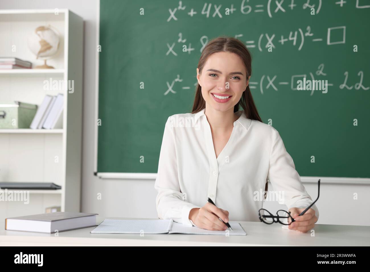 Young math’s teacher giving lesson at table in classroom Stock Photo ...