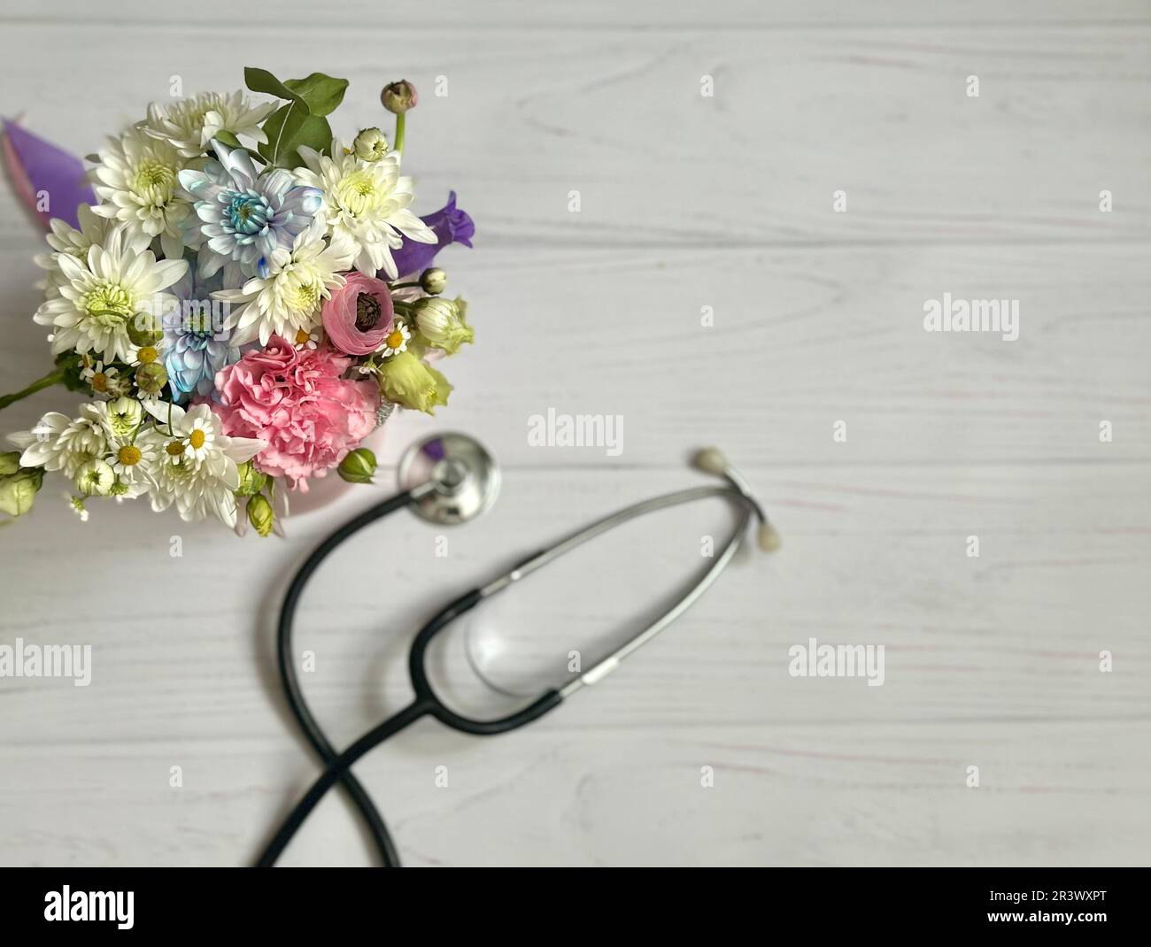 Stethoscope and beautiful flowers on the light wooden background ...
