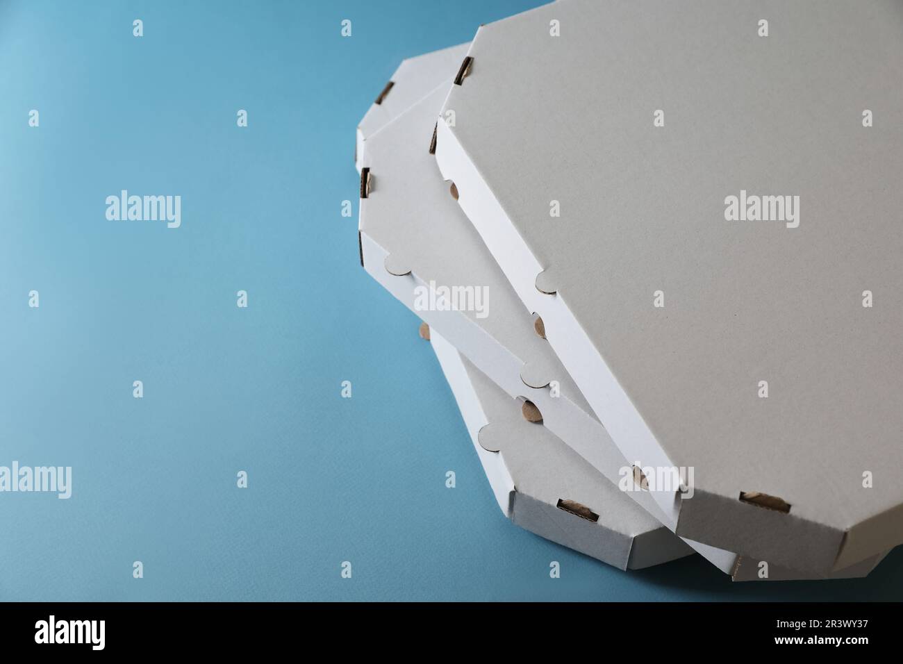 Stack of empty pizza boxes on light blue background, closeup. Space for ...