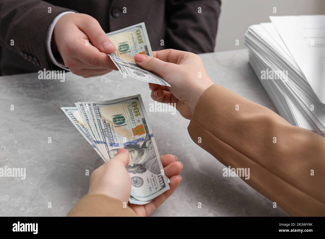 Woman giving money to man at light grey table, closeup. Currency ...