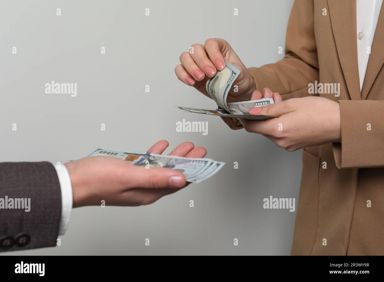 Woman giving money to man on light grey background, closeup. Currency ...