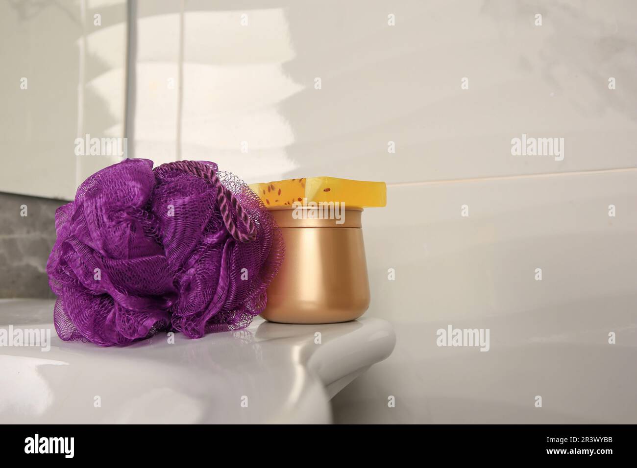 Purple shower puff and cosmetic products on sink in bathroom, space for ...