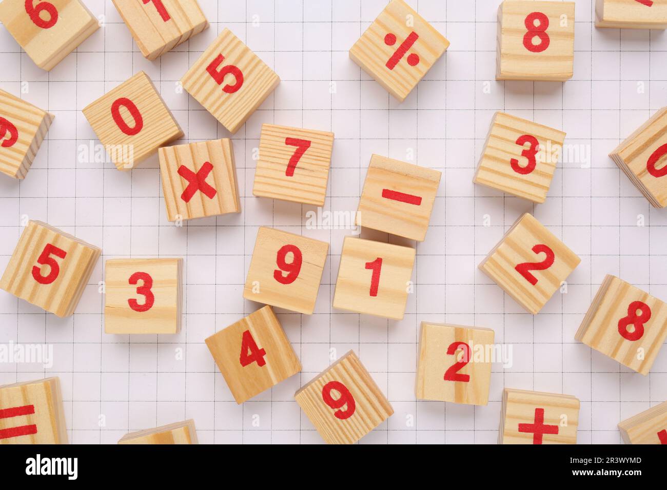Wooden cubes with mathematical symbols and numbers on sheet of grid ...