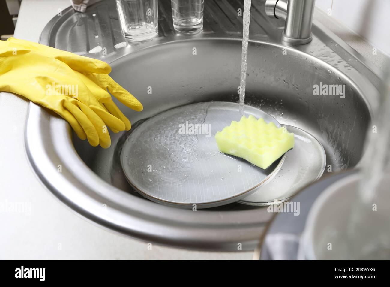 Washing plates, sponge and rubber gloves in kitchen sink Stock Photo ...