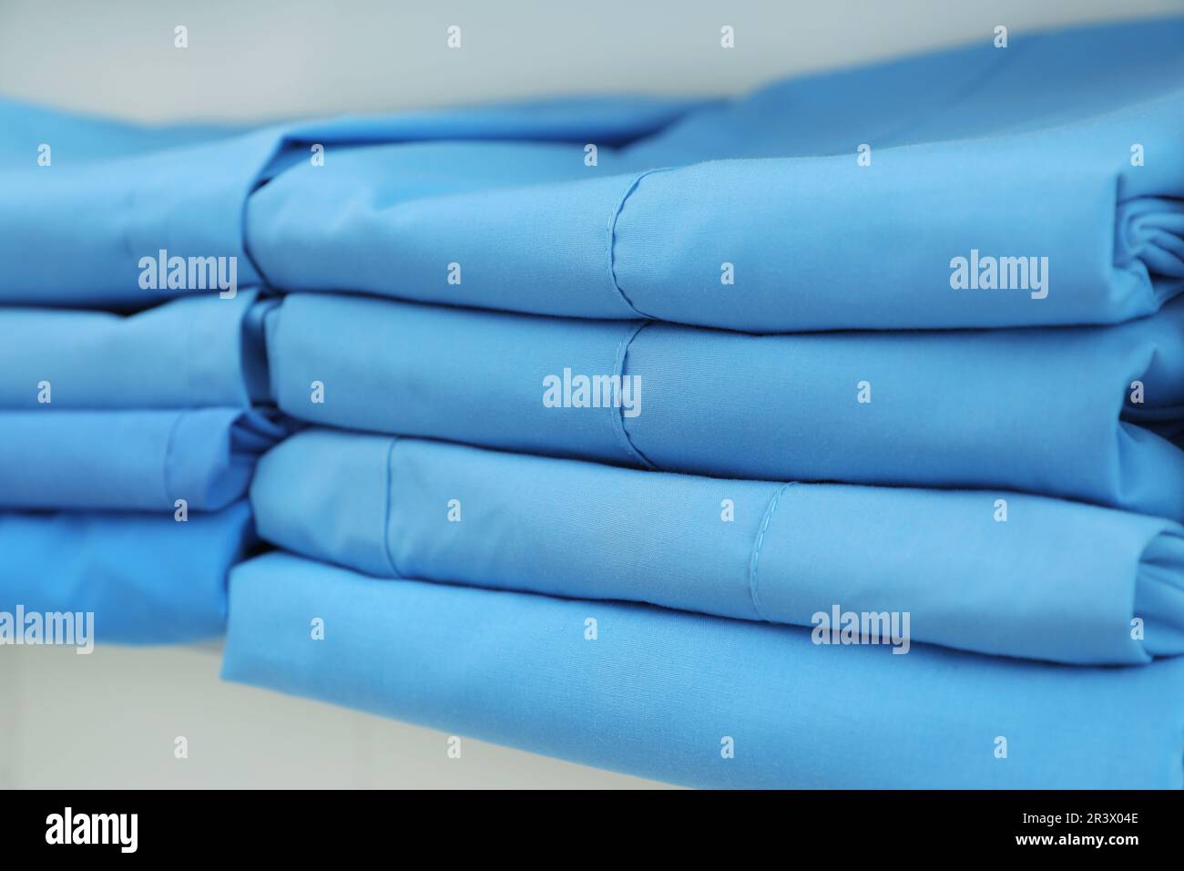 Light blue medical uniforms on white rack, closeup Stock Photo - Alamy