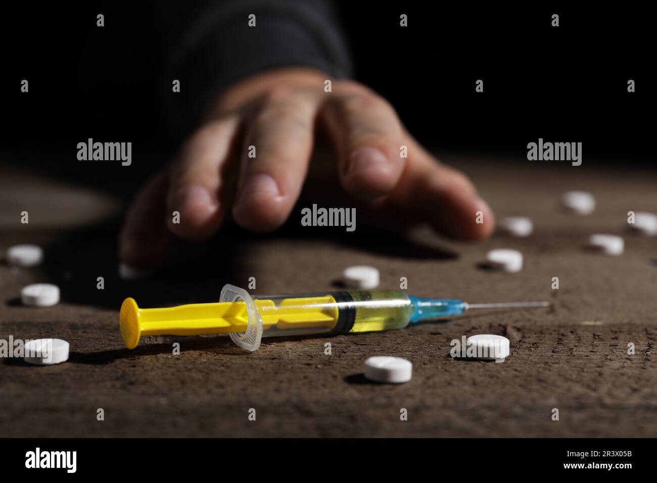 Addicted man reaching to drugs at wooden table, focus on syringe Stock ...