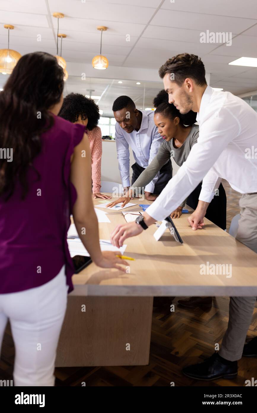 Vertical image of diverse female and male businesspeople talking and ...