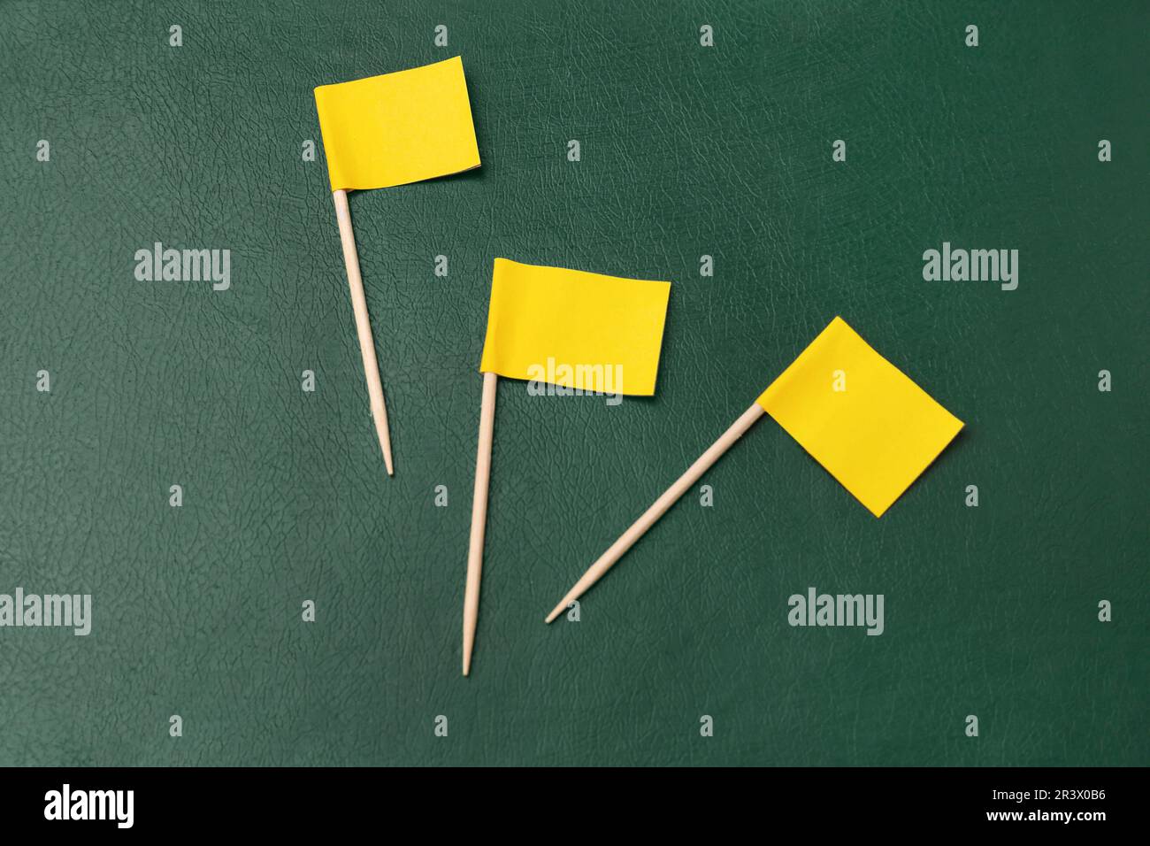 Small yellow paper flags on green background, flat lay Stock Photo - Alamy