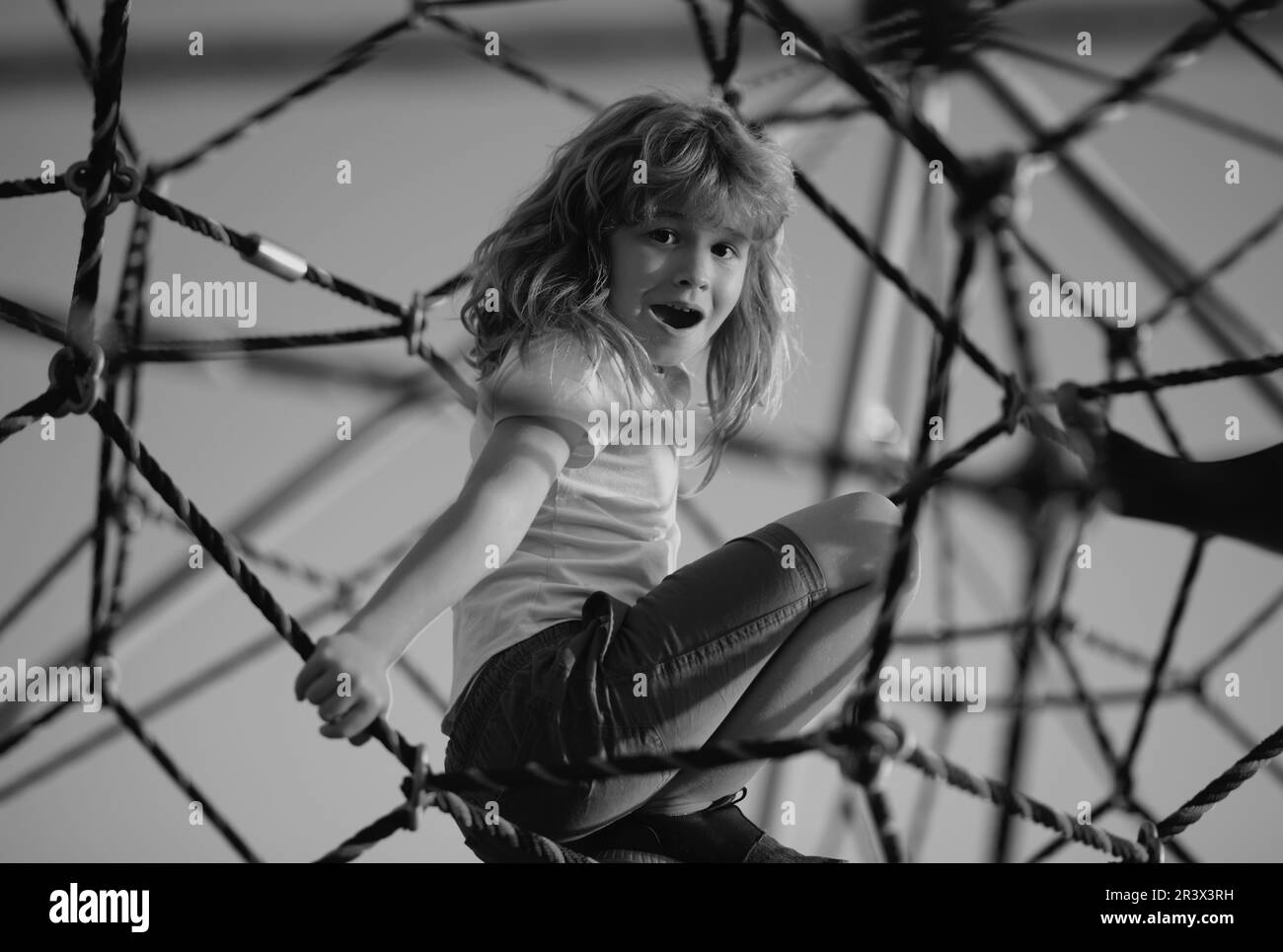 Child climbing the net. Child boy climbed on top of the rope web on ...