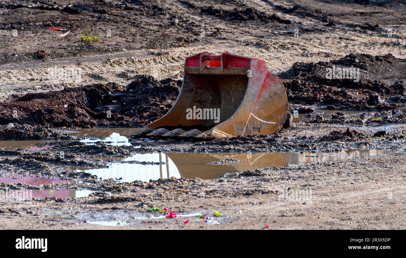 red excavator shovel lying on muddy soil Stock Photo - Alamy