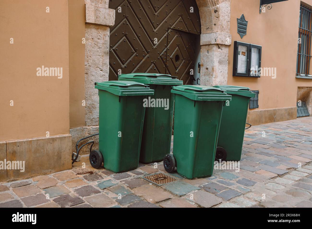 A large and small green trash can near cafe on a city street. Sorting ...
