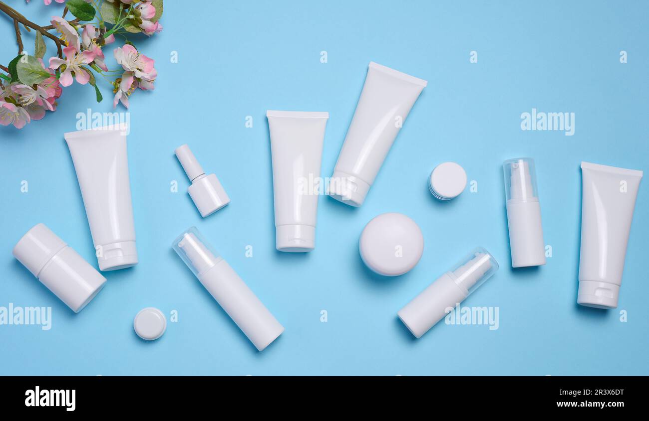 White plastic tubes, jars, and containers for cosmetic products on a ...