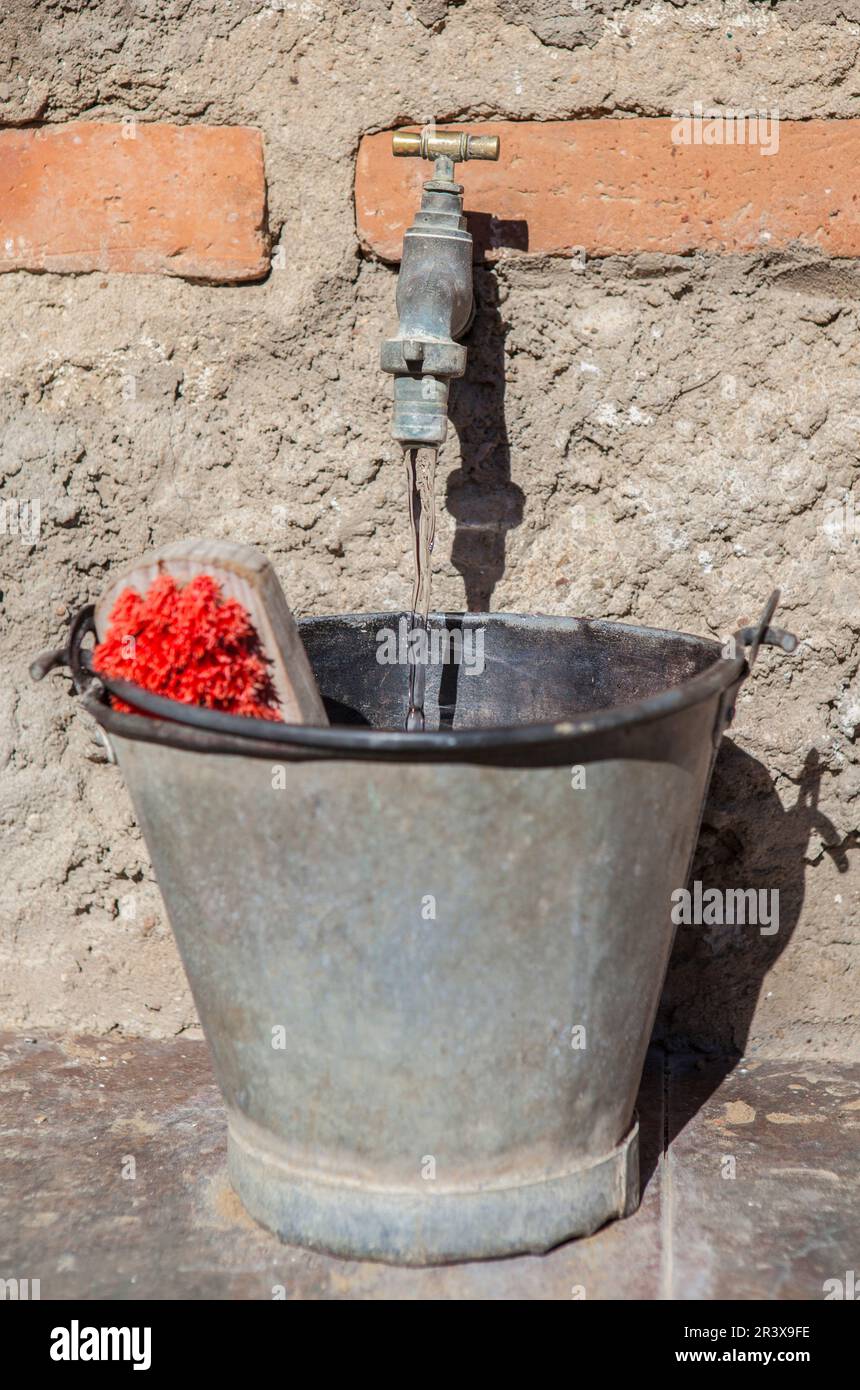 Faucet filling from a metal bucket with a scrubbing brush. Selective ...