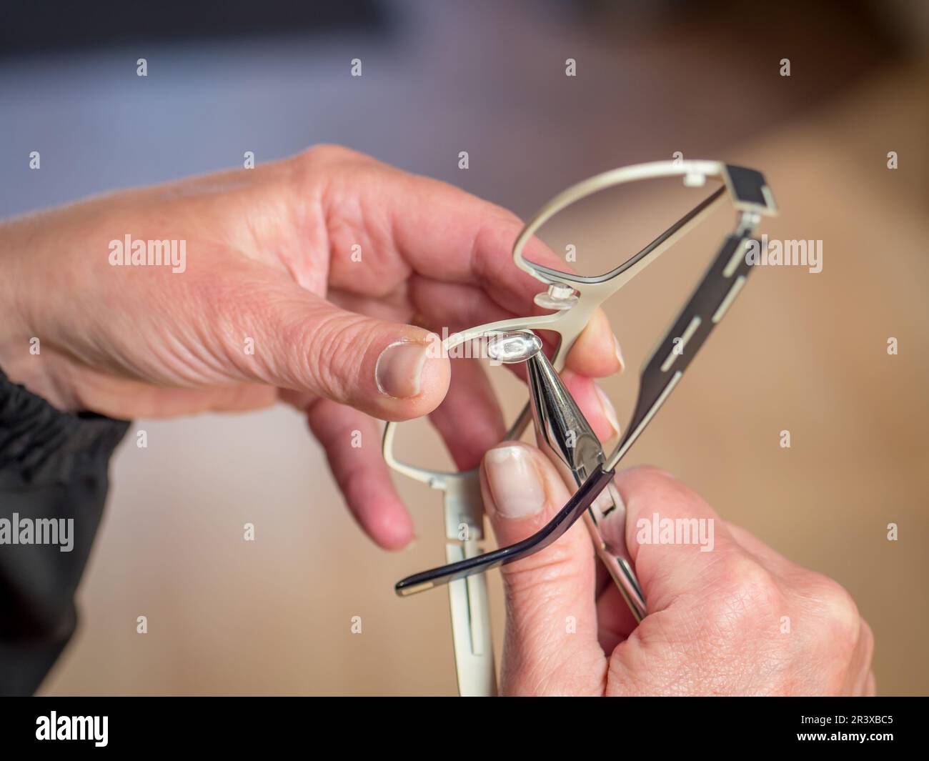 Optician preparing a pair of glasses. Adjustment of the nose pads Stock ...