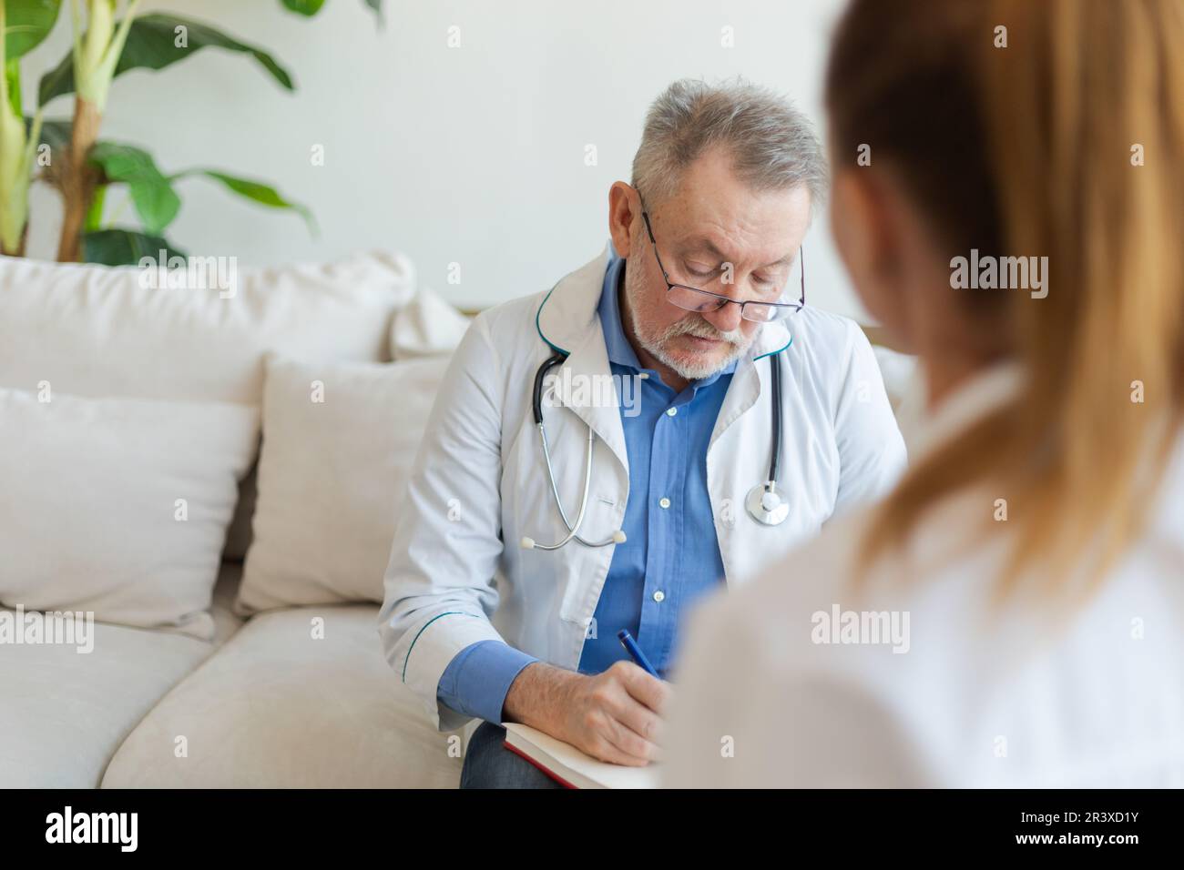 Senior man doctor examining yound woman in doctor office or at home ...