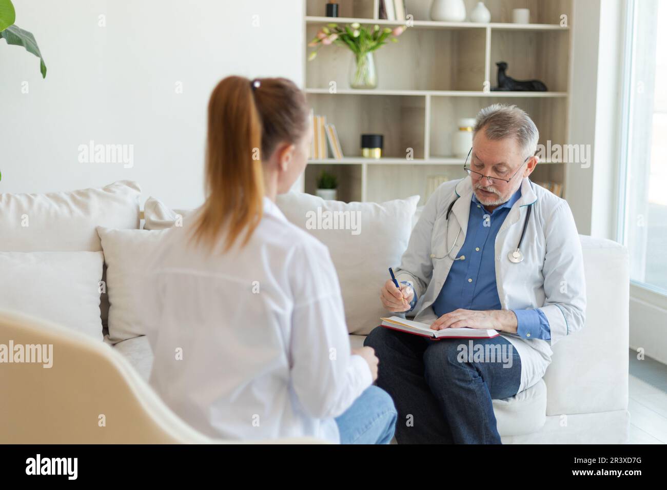 Senior man doctor examining yound woman in doctor office or at home ...