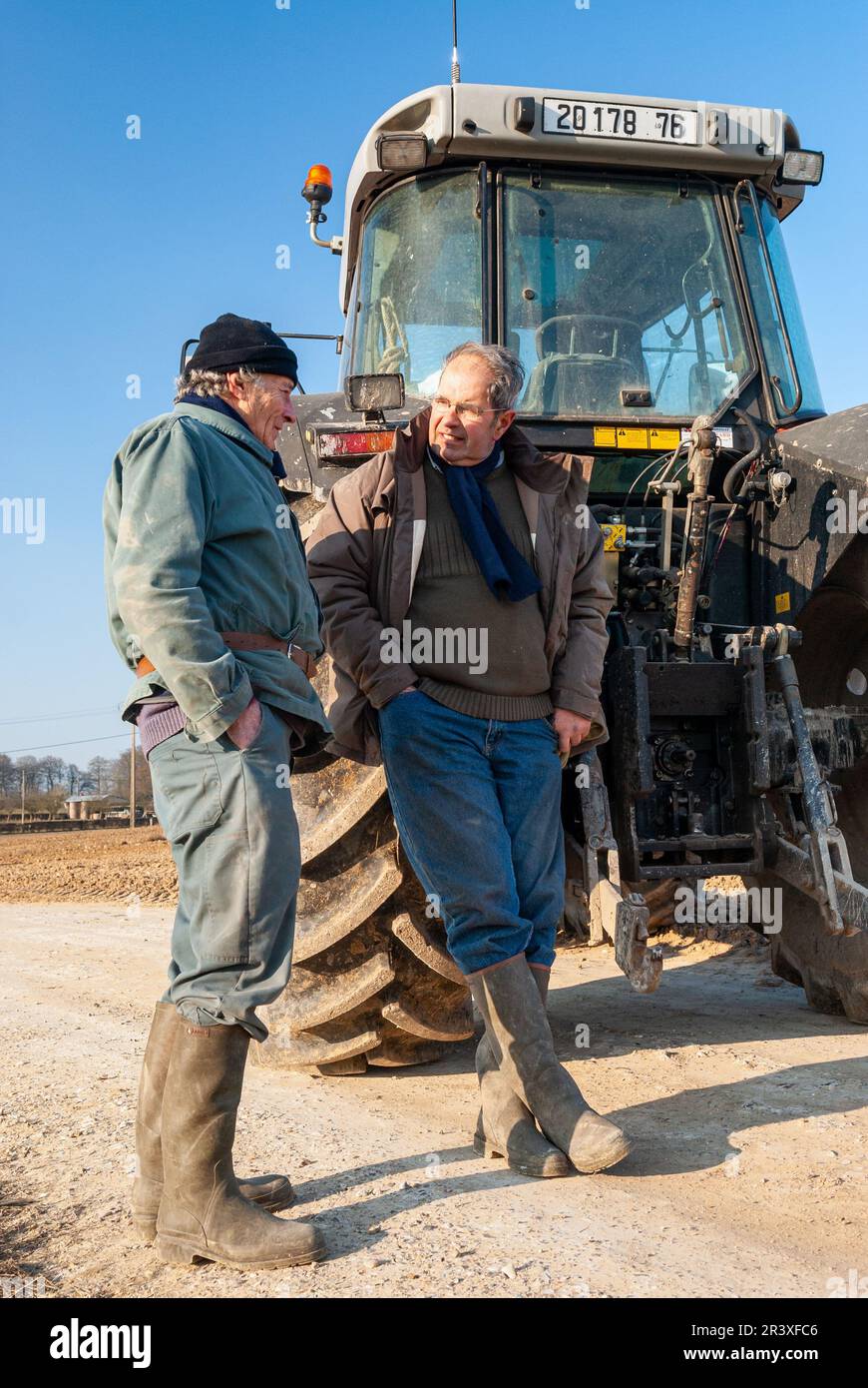 Farmers' retirement pension: two farmers talking near a tractor, one ...