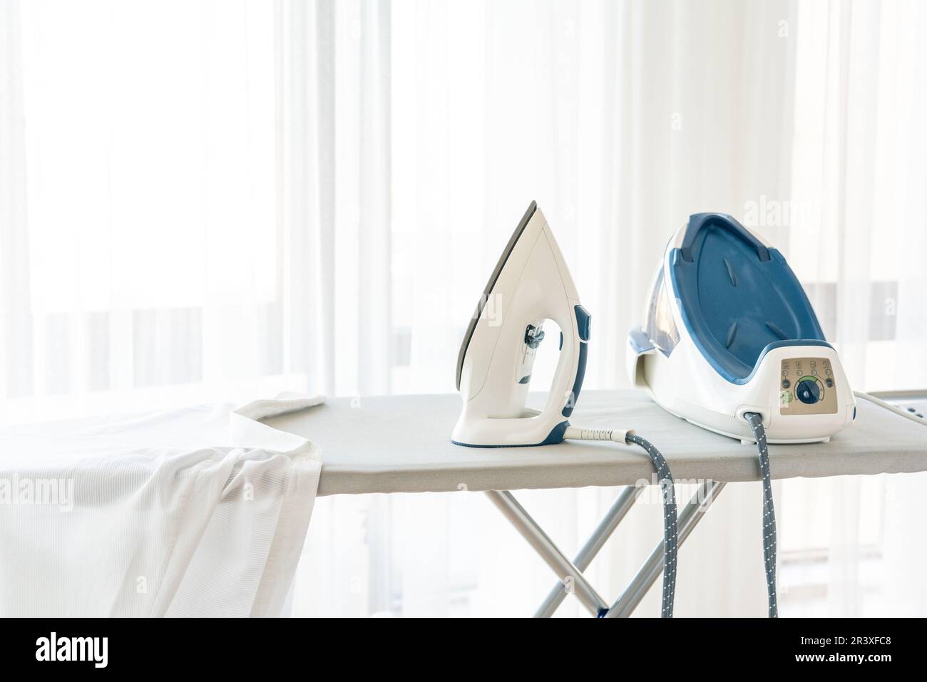 Steam iron standing on ironing board near window with copy space Stock ...