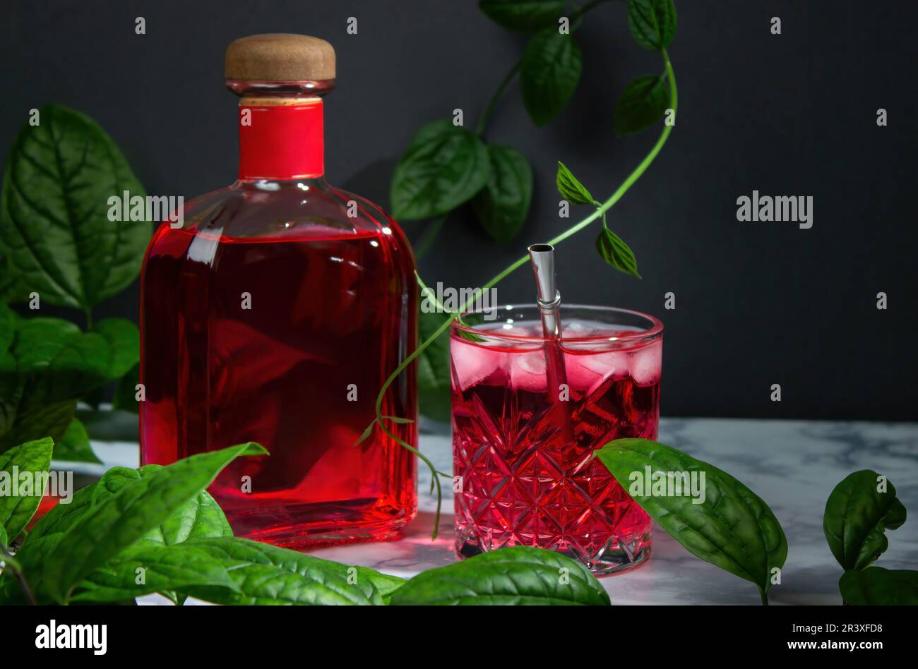 A bottle of red alcohol, next to it in an old-fashioned glass is a ...