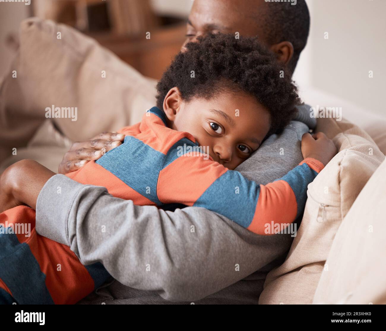 Love, portrait and boy hugging his father while relaxing on sofa in the ...