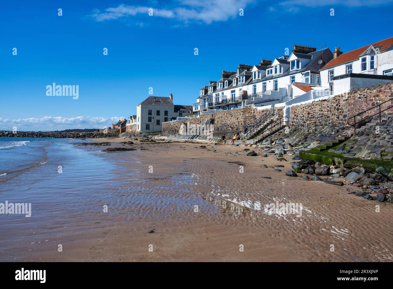 View looking south along sandy beach to jetty at Scottish coastal town ...