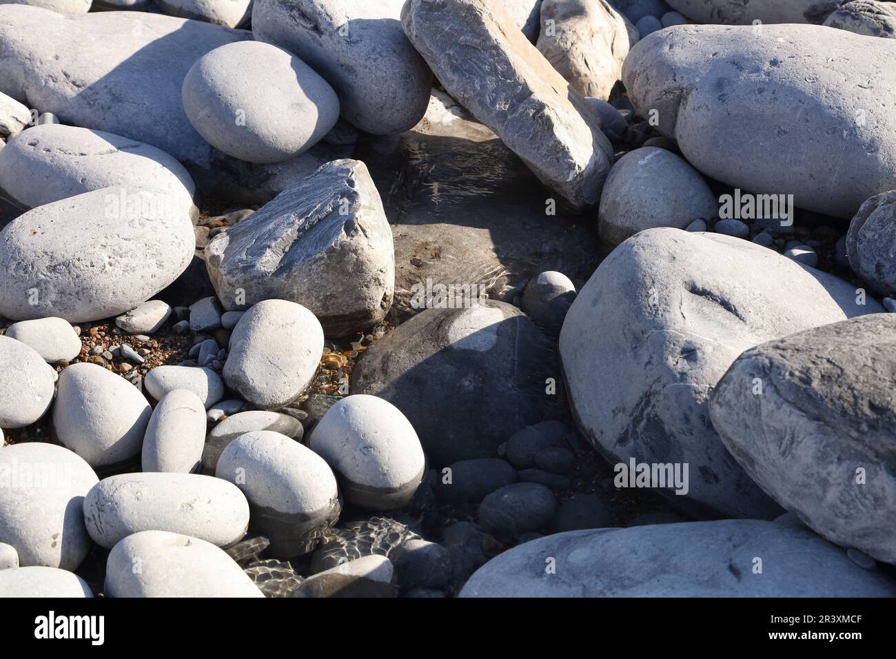 A small pile of large pebbles with running water flowing through under ...