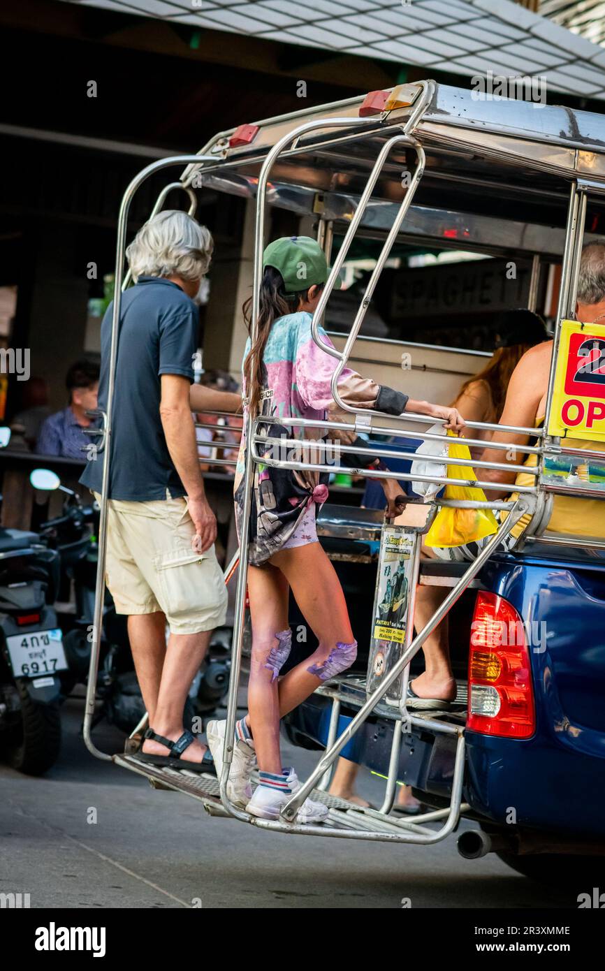 Passengers hold on to the back of the baht bus as it makes its way ...