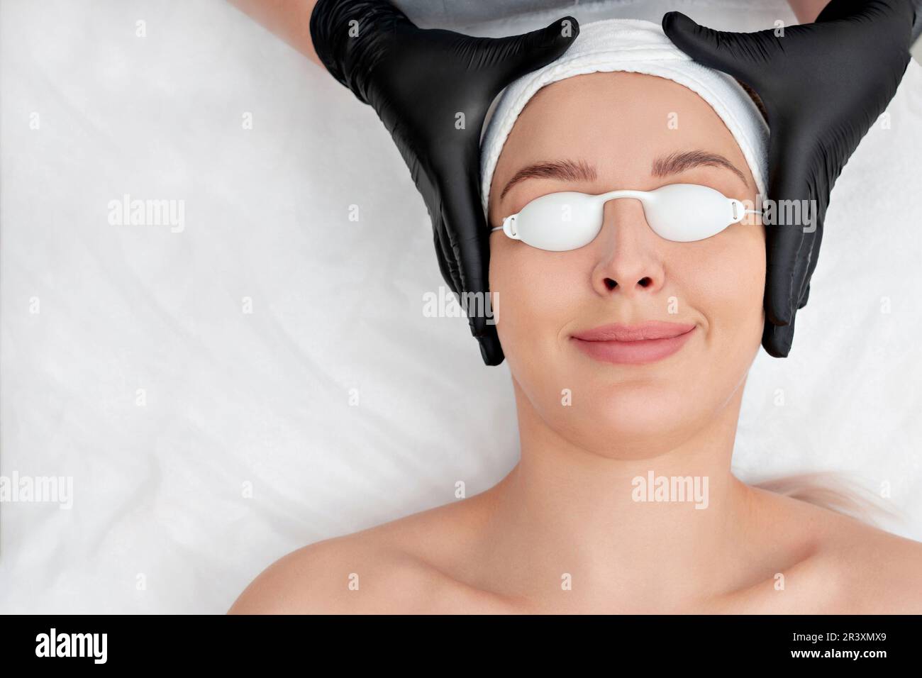 Beautiful young woman with covered eyes is getting face skin treatment ...
