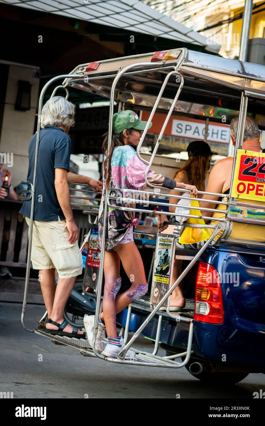 Passengers hold on to the back of the baht bus as it makes its way ...