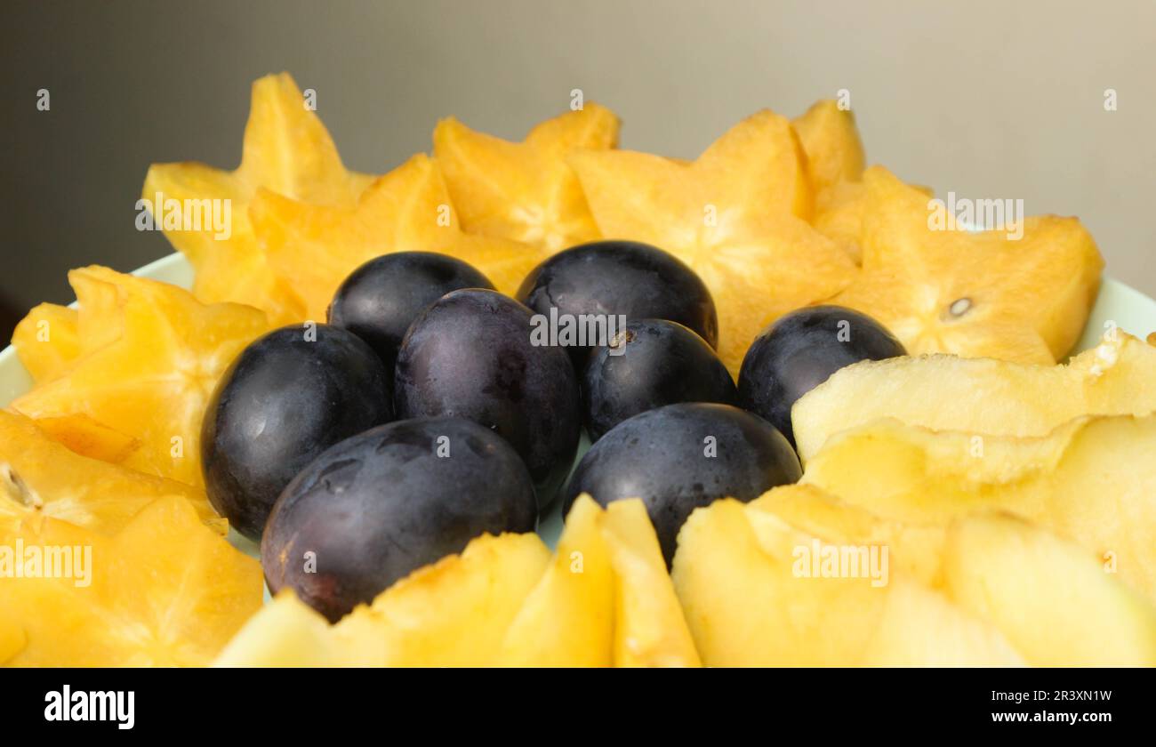 Fruits on the plate, pieces of apple, starfruit, and grapes on the ...