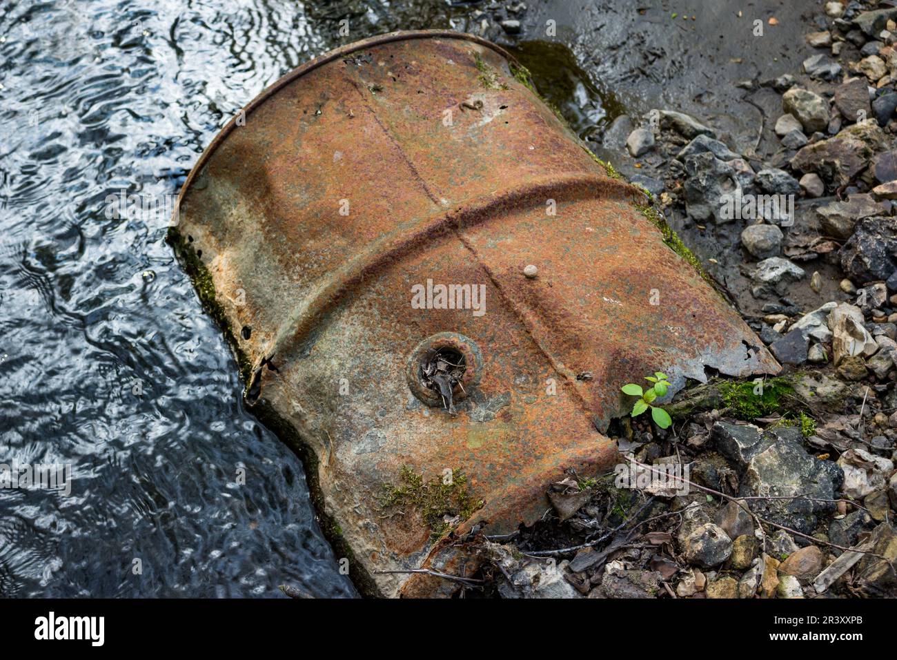 Old unnecessary rusty barrel lying in the river, collecting scrap metal ...