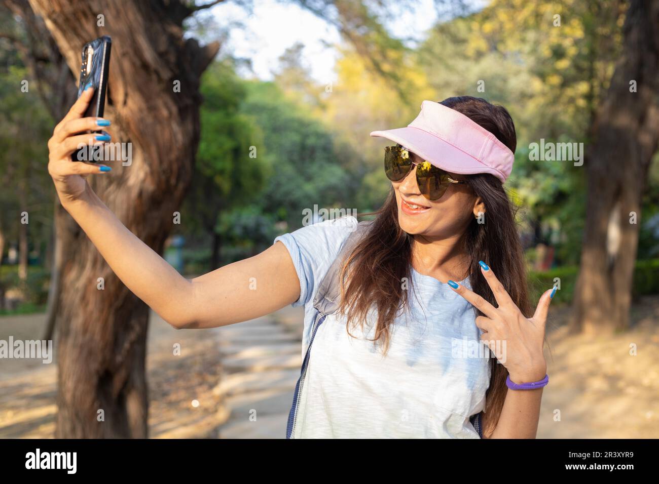 Young indian travel woman wearing sunglasses and cap taking selfie ...