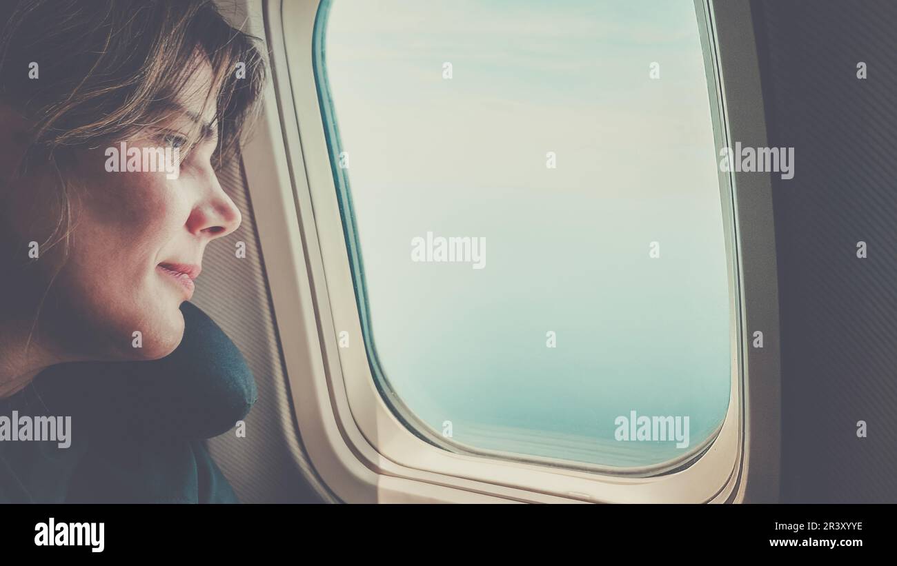 Beautiful girl looks out the window of the airplane. Summer vacation ...