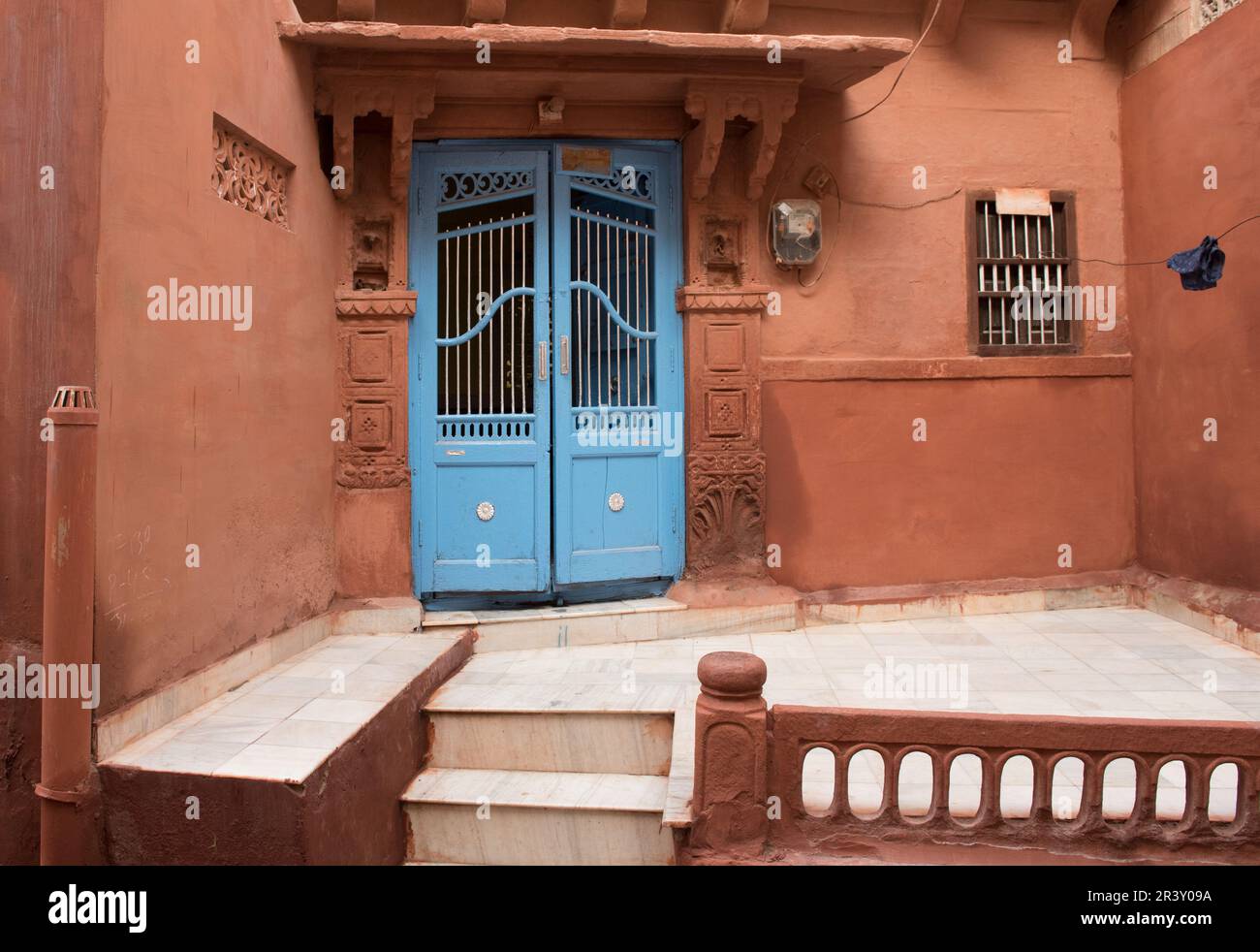 Facade of a traditional Indian red house courtyard with blue door ...