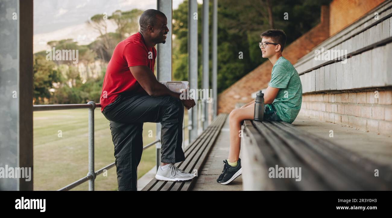 Sports coach talking to his student outside in a school. Physical ...