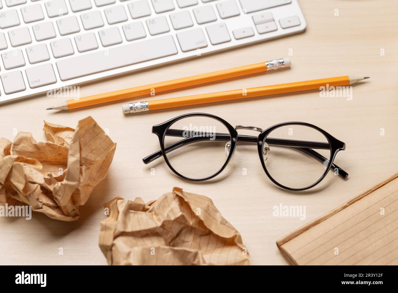 Top view of blank notepad, keyboard, eyeglasses and crumpled papers on ...