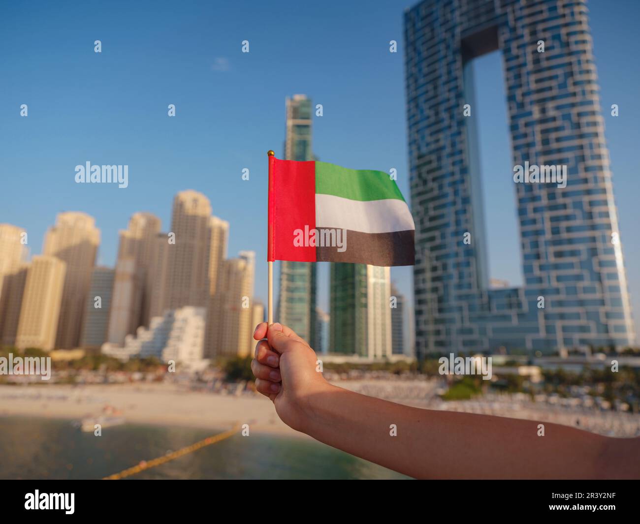 Close up of a female hand holding tiny flag of UAE against Dubai ...