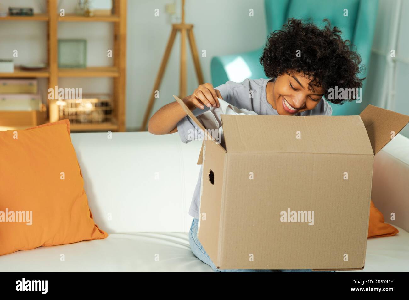 African girl unpacking delivery looking in box. Happy woman opening ...