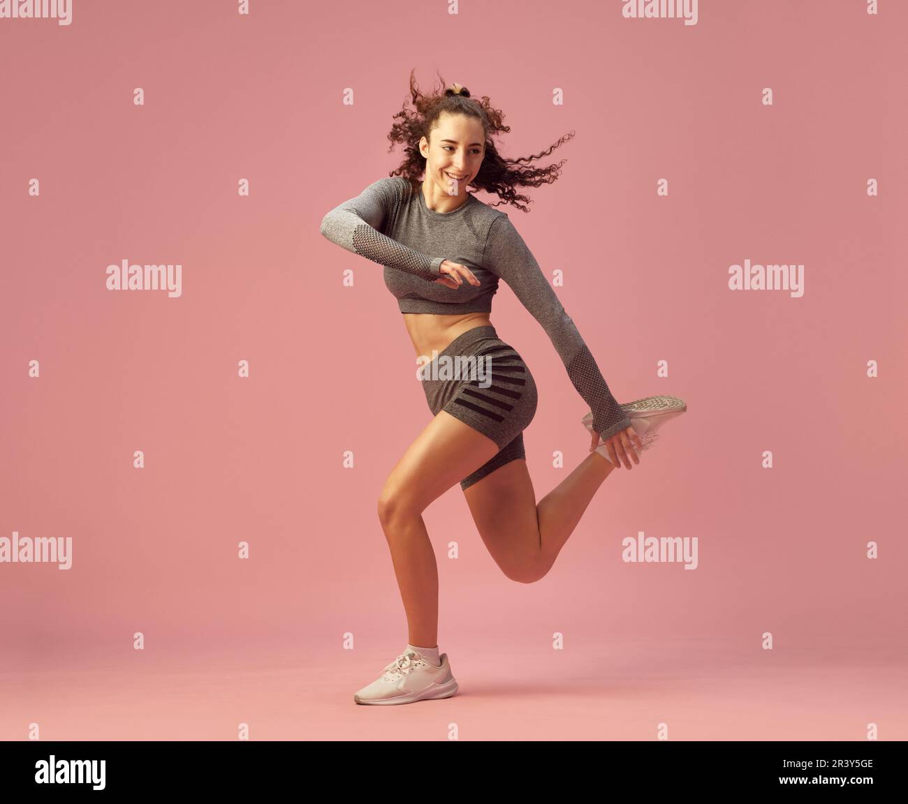Dynamic image of sportive young girl in gray sportswear training ...