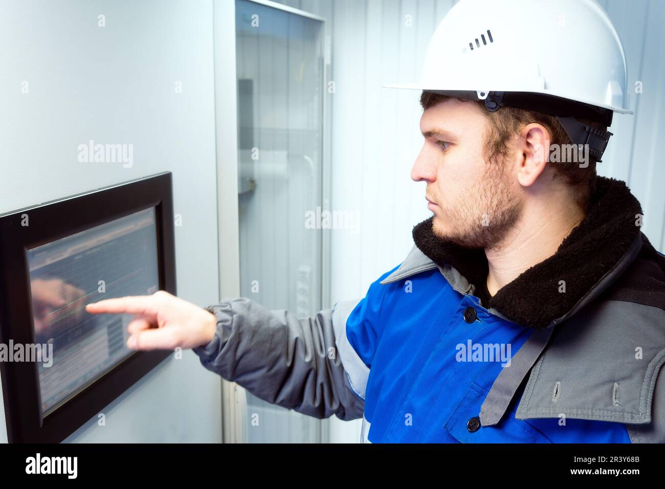 Engineer in hard hat and winter pea coat presses his finger on touch ... Engineer in hard hat and winter pea coat presses his finger on touch ...