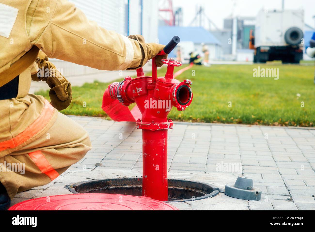Firefighter sits next to fire hydrant. Back view. Firemen training ...