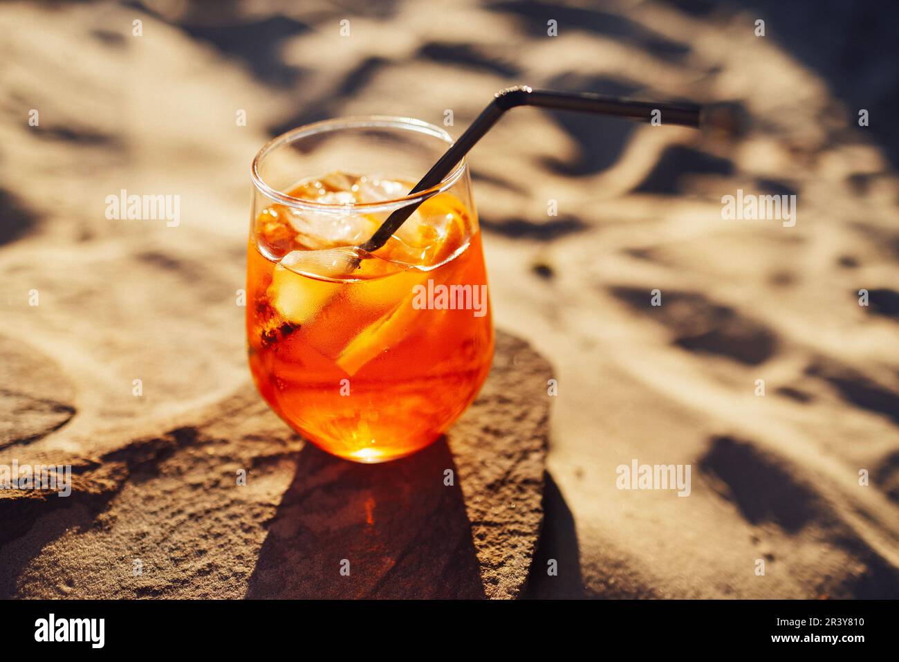 Orange slice and aperol spritz cocktail on a stone against the backdrop ...