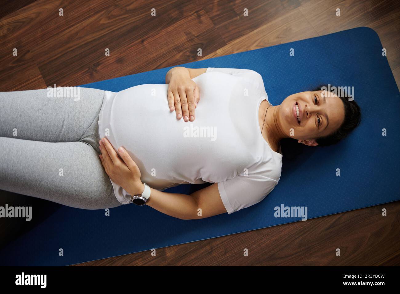 Top view pregnant woman caresses her belly, smiles at camera during ...