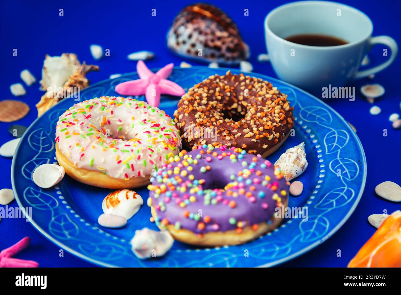 Assorted donuts in a plate on a blue background. Around them are ...
