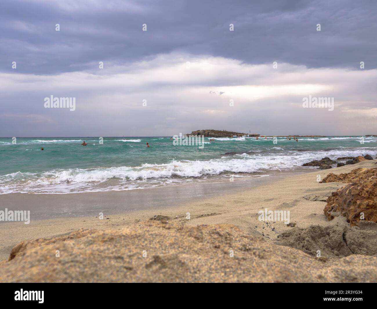 People swim in sea waves on an overcast day. Picturesque Nissi beach ...