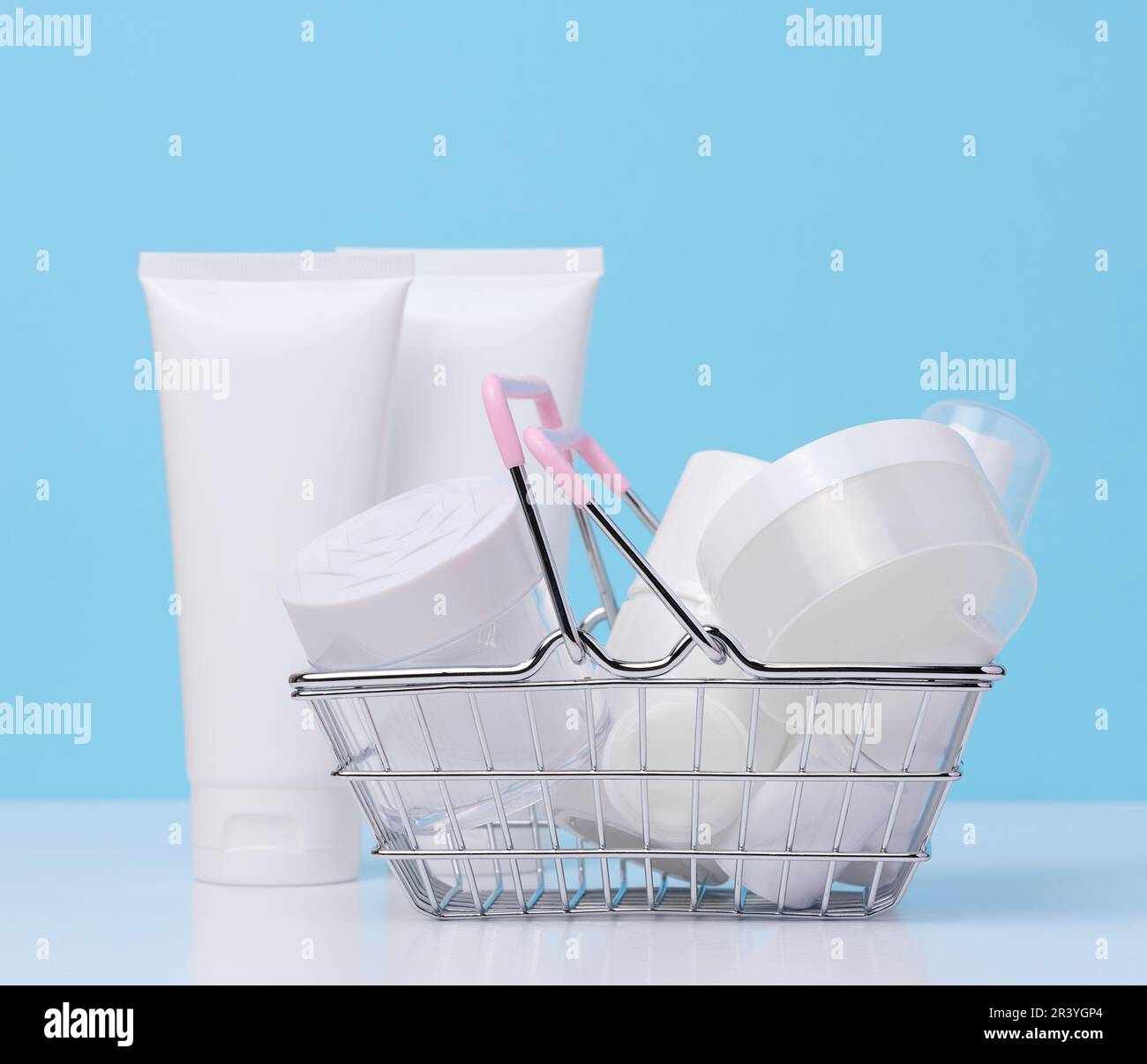 White plastic tubes, jars in a miniature metal basket, containers for ...