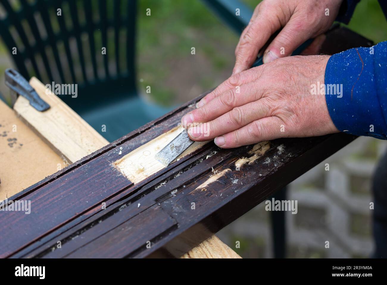 Hands of a man processing wooden elements with a chisel. Professional ...