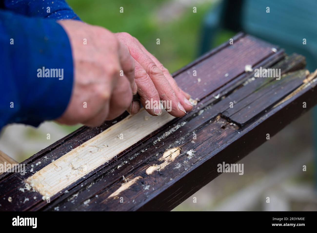 Hands of a man processing wooden elements with a chisel. Professional ...