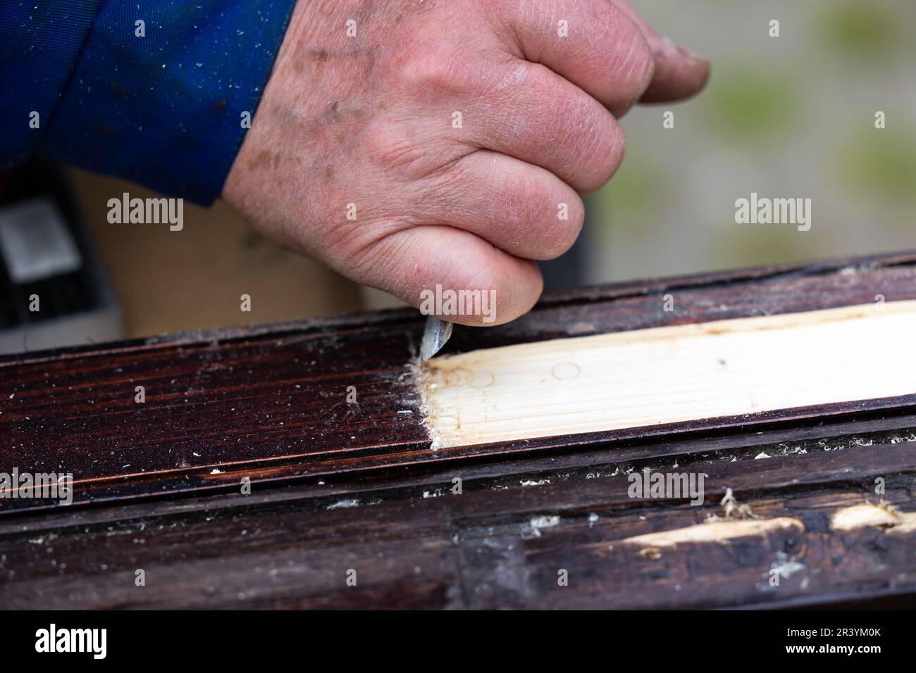 Hands of a man processing wooden elements with a chisel. Professional ...