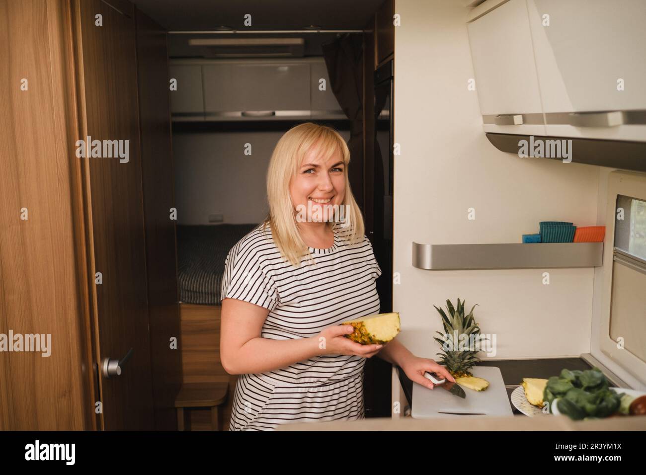 a woman cooking food in the kitchen inside a motorhome, the interior of ...